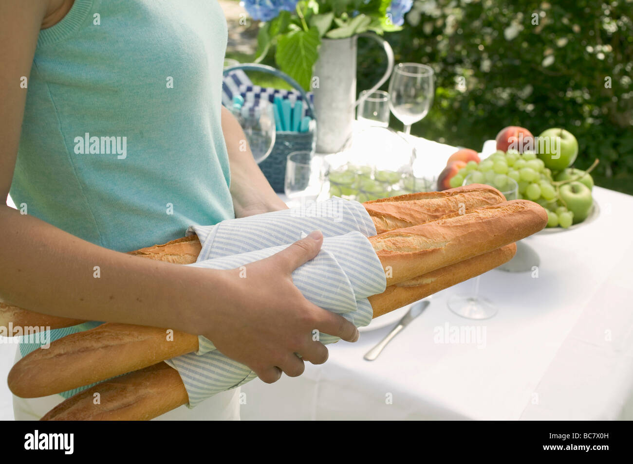 Woman carrying baguettes to table laid out of doors Stock Photo - Alamy