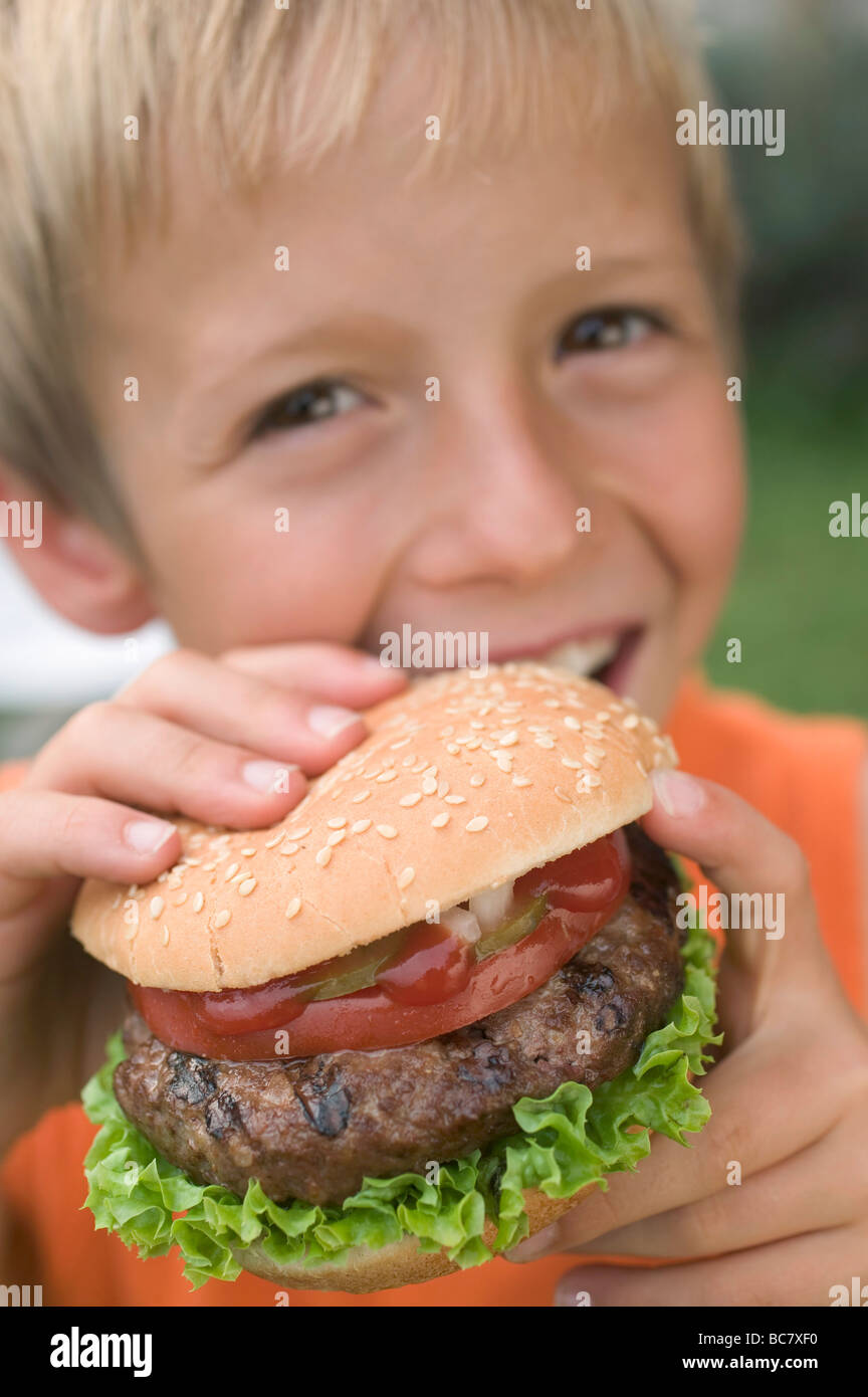 Small boy eating hamburger Stock Photo - Alamy