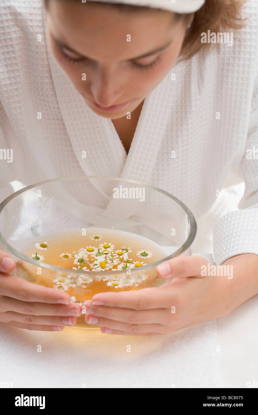 Woman bending over bowl of chamomile tea with flowers Stock Photo - Alamy