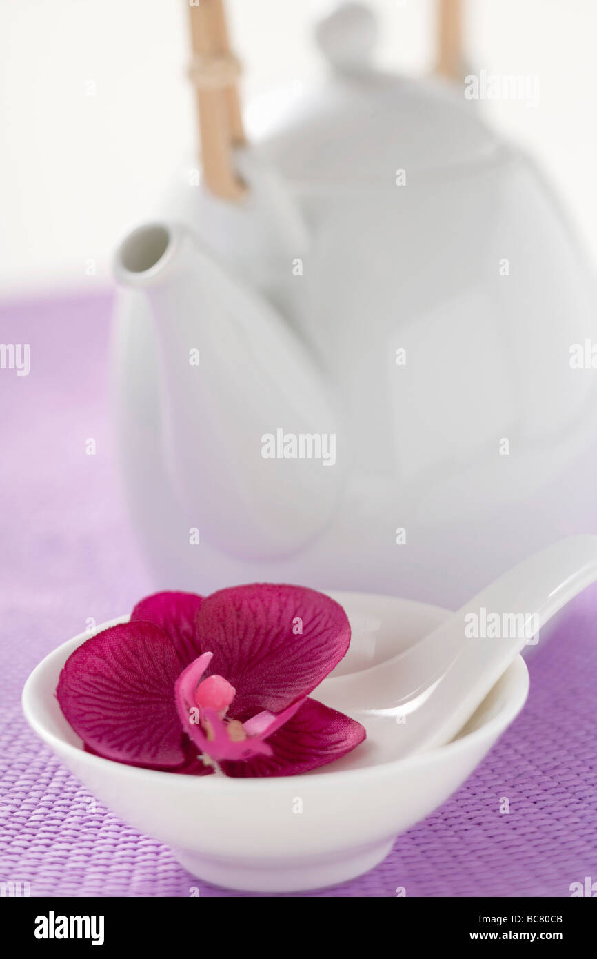 Teapot and bowl with spoon and orchid Stock Photo - Alamy