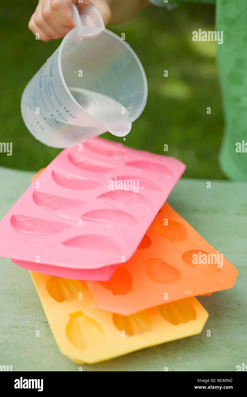 Child pouring water into ice cube tray Stock Photo - Alamy