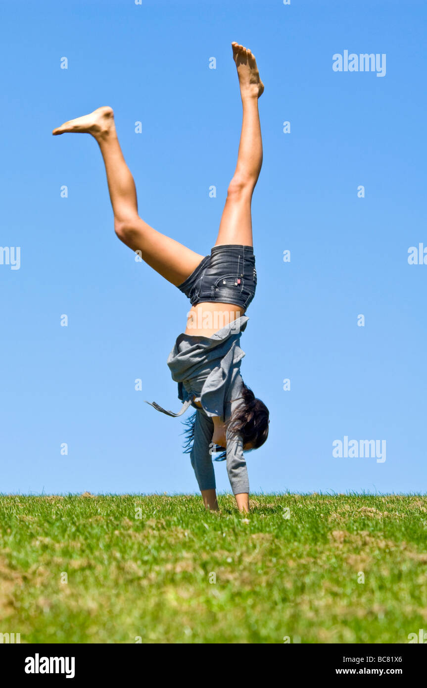 Vertical portrait of an attractive young teenage girl doing a handstand ...