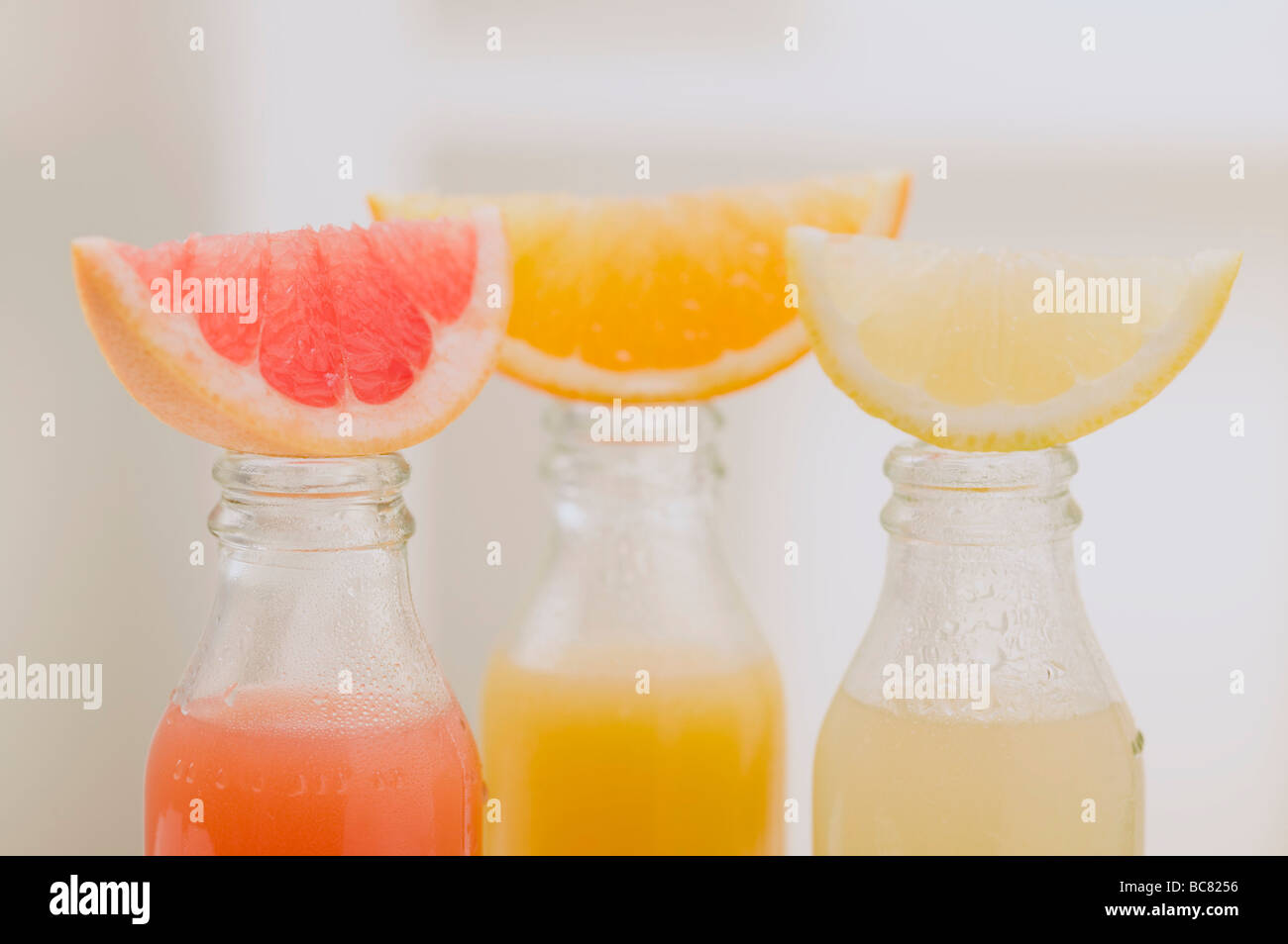 Three fruit juices in bottles with wedges of fresh fruit Stock Photo ...