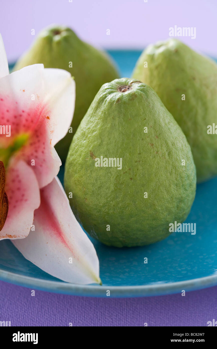 Three guavas on plate with orchid Stock Photo - Alamy