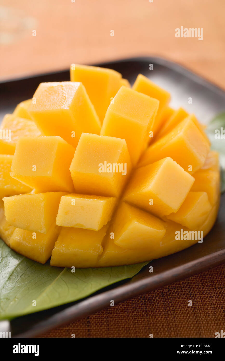 Diced mango still attached to the skin on brown plate Stock Photo - Alamy