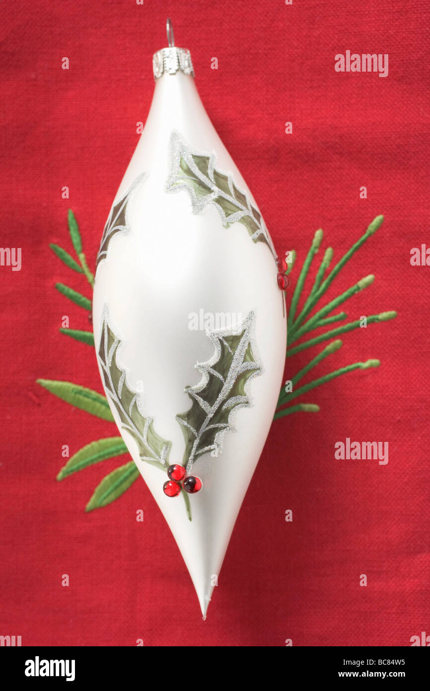 White tear-drop shaped Christmas bauble on red linen cloth Stock Photo ...