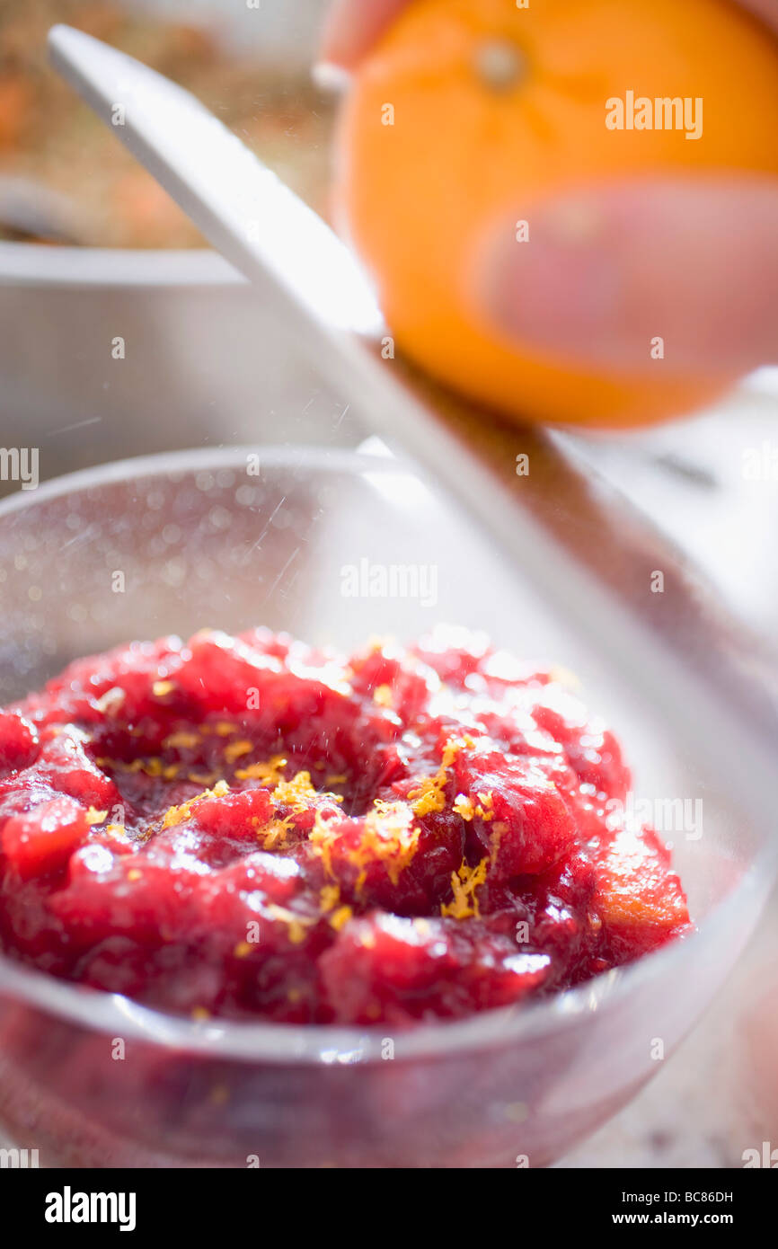 Grating orange zest into cranberry sauce Stock Photo - Alamy