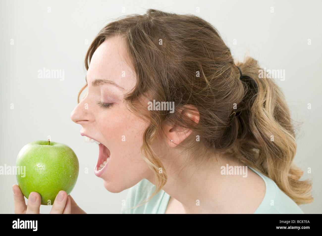 Woman biting into green apple Stock Photo - Alamy