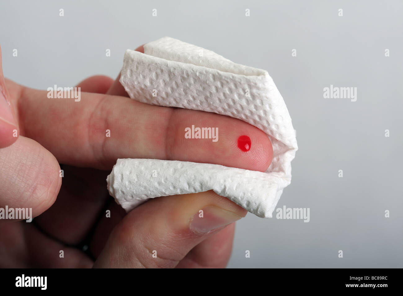 Kitchen roll wrapped around pin prick of blood on finger Stock Photo ...