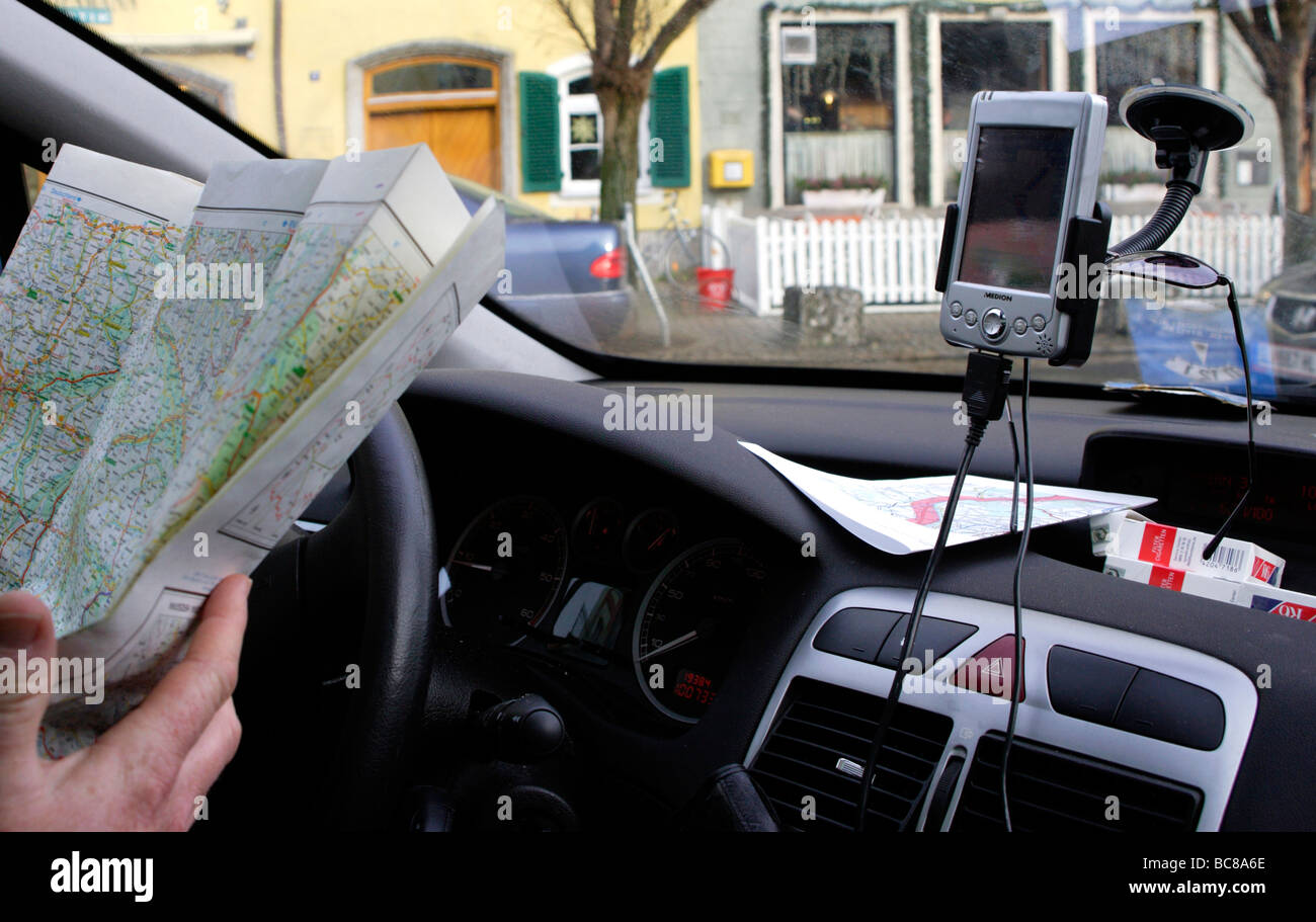 Man holding a conventional street map with portable GPS system in motor ...