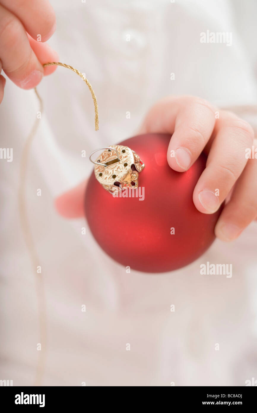 Child threading string through top of Christmas bauble Stock Photo - Alamy