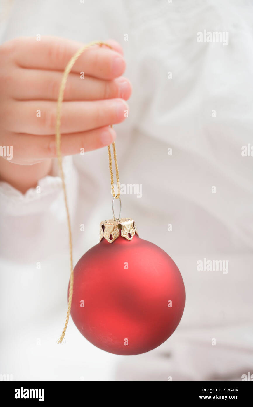 Child holding Christmas bauble with gold string Stock Photo - Alamy