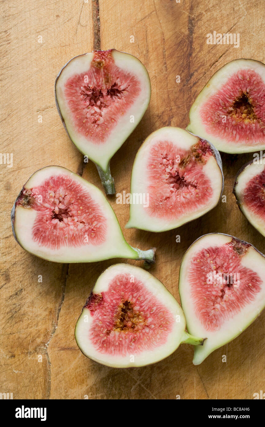 Several fig halves on wooden background Stock Photo - Alamy