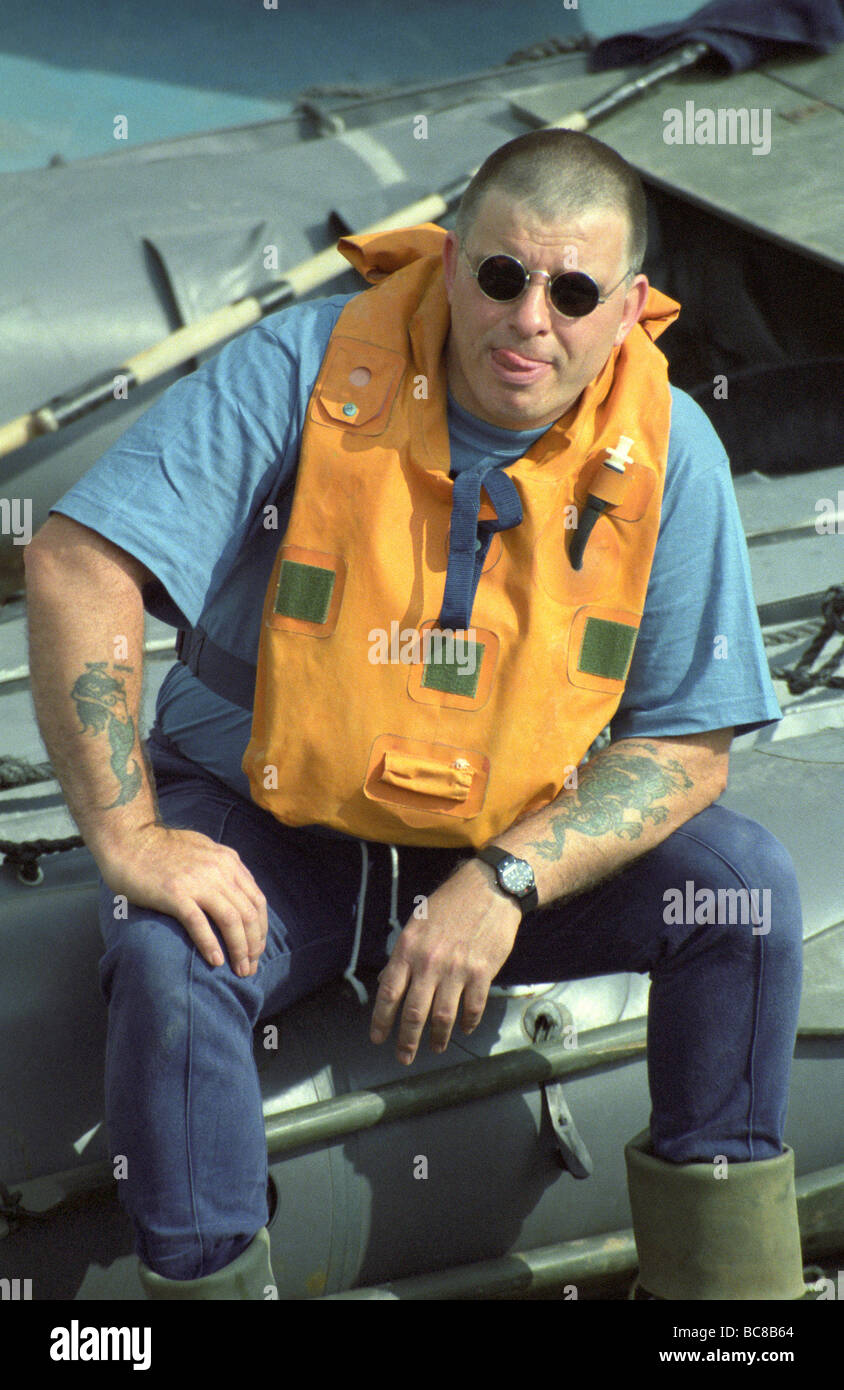 salty male sailor sitting on rubber boat wearing orange life jacket ...