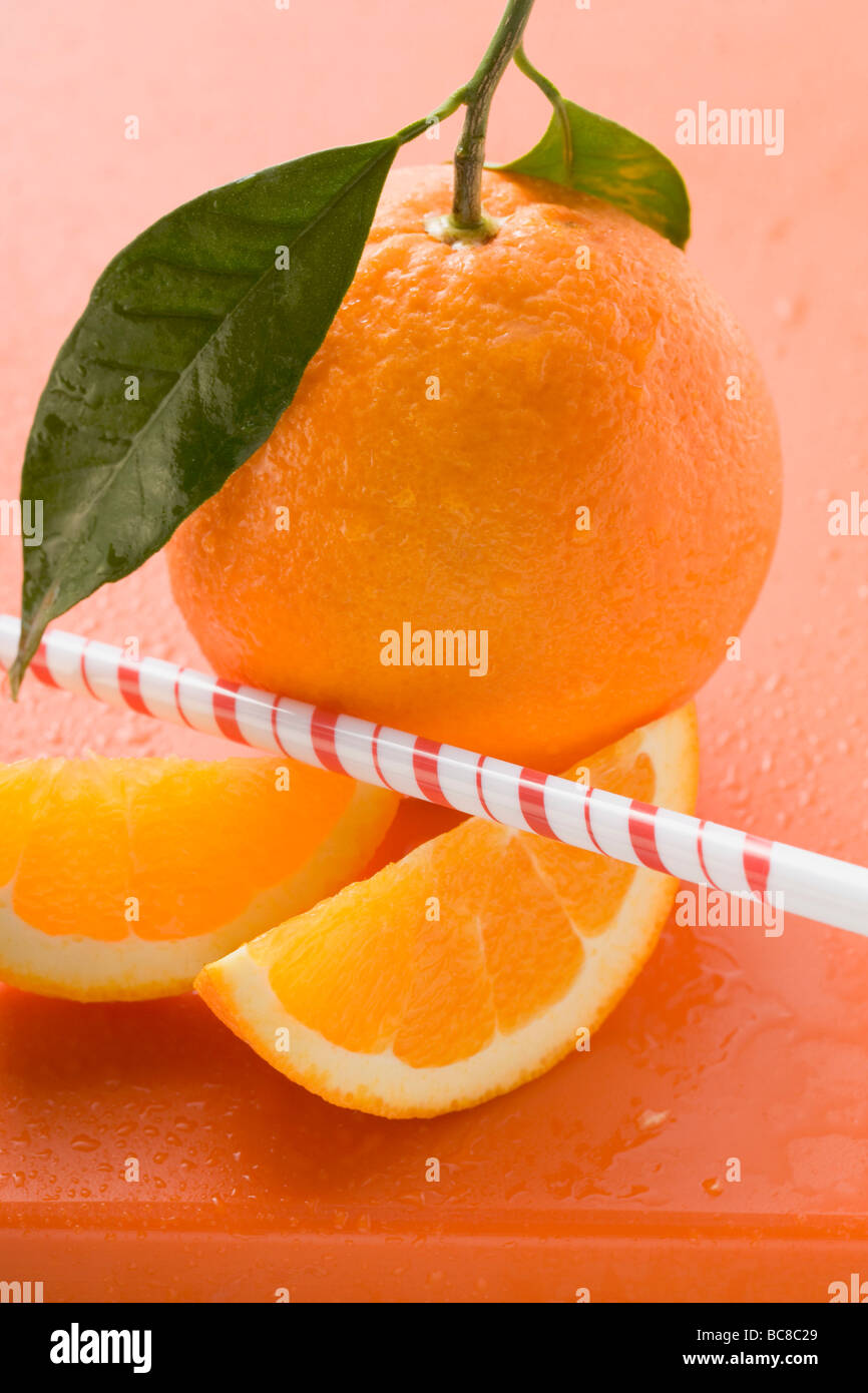 Orange with stalk and leaf, orange wedges, straw Stock Photo - Alamy