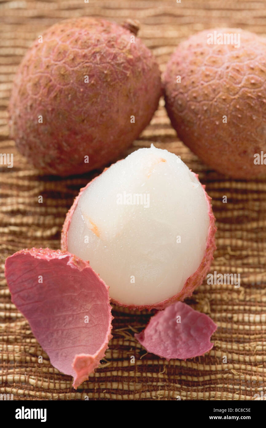 Three lychees, one half-peeled Stock Photo - Alamy
