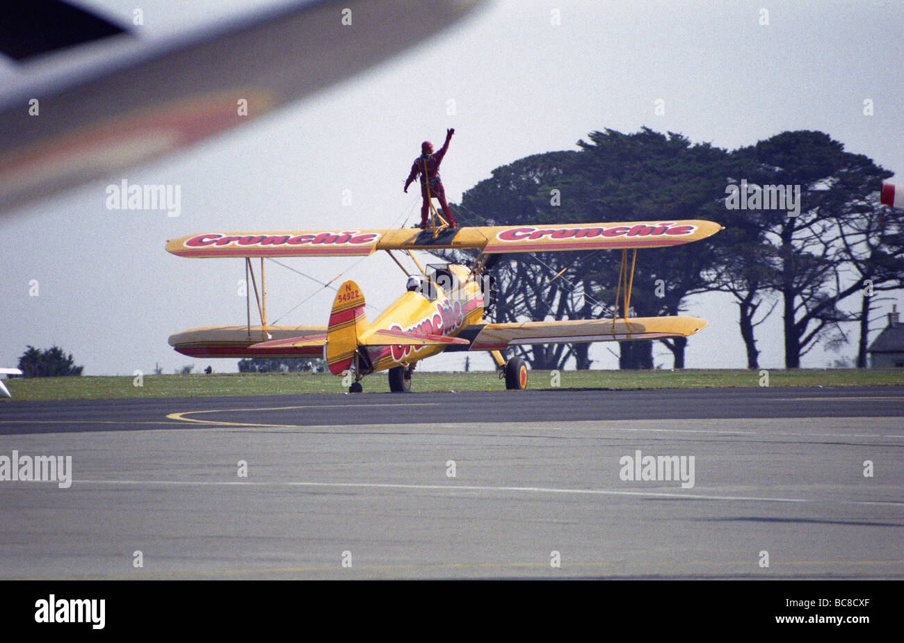 wingwalker on top of yellow Biplane about to take off on runway at ...