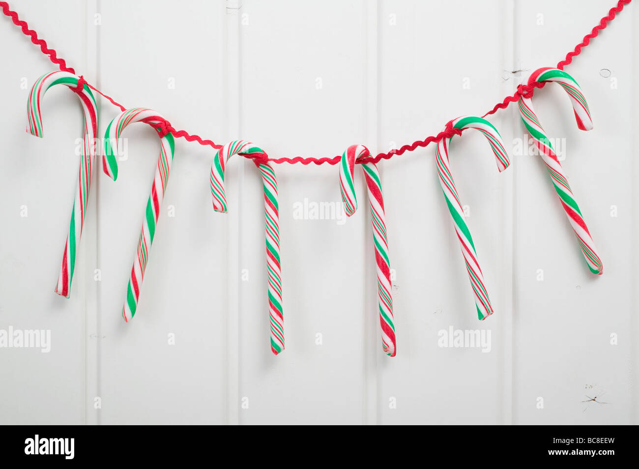 Several candy canes hanging on red ribbon Stock Photo - Alamy