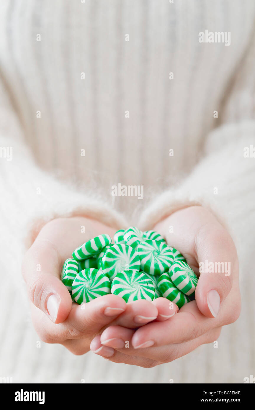 Hands holding green and white striped peppermints Stock Photo - Alamy