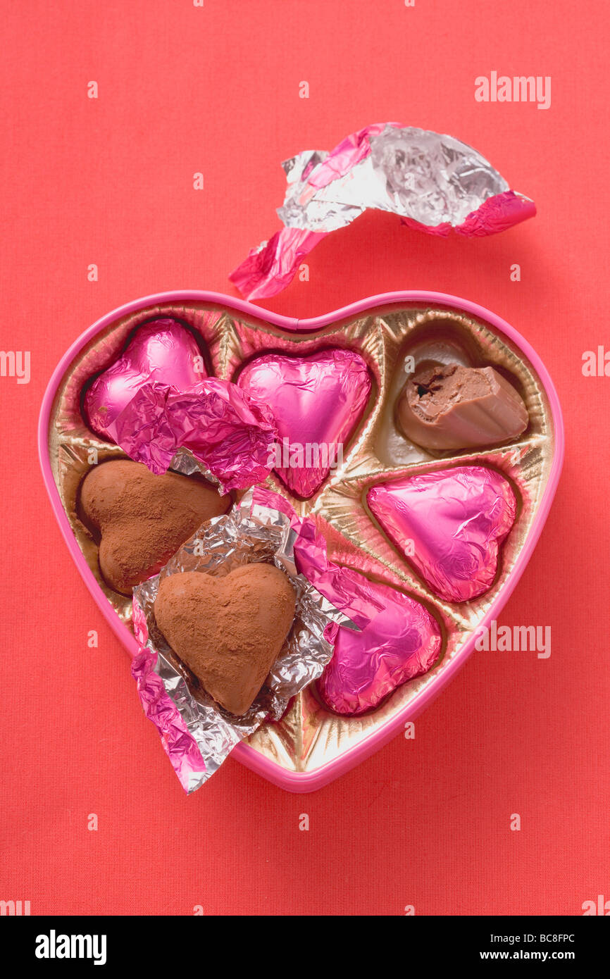 Pink chocolates in heart-shaped box (one partly eaten Stock Photo - Alamy