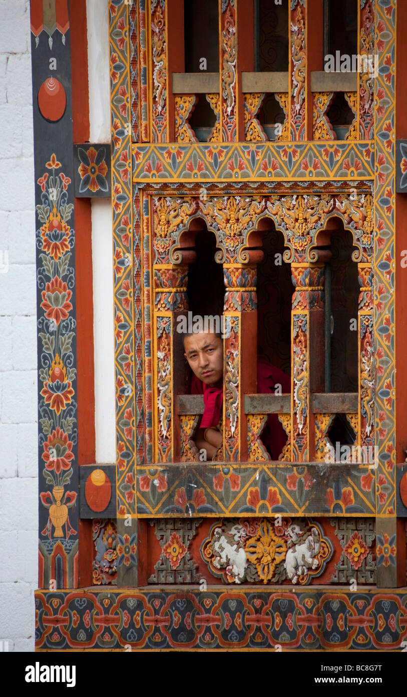 Monk looking out from balcony decorated windows at Punakha Dzong ...