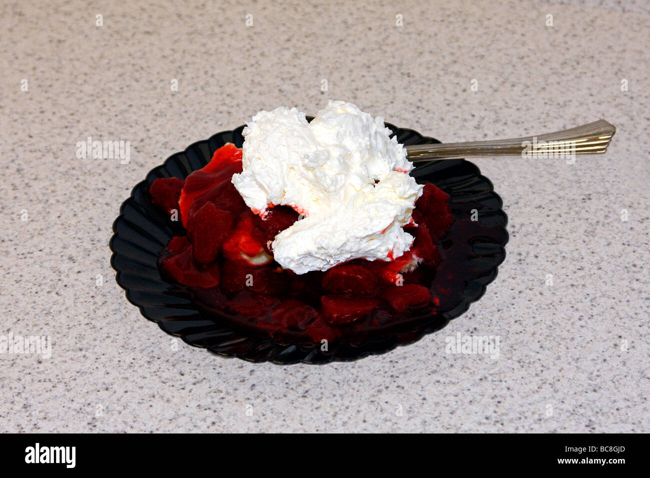 Strawberry Shortcake on small black plate with fork Stock Photo - Alamy