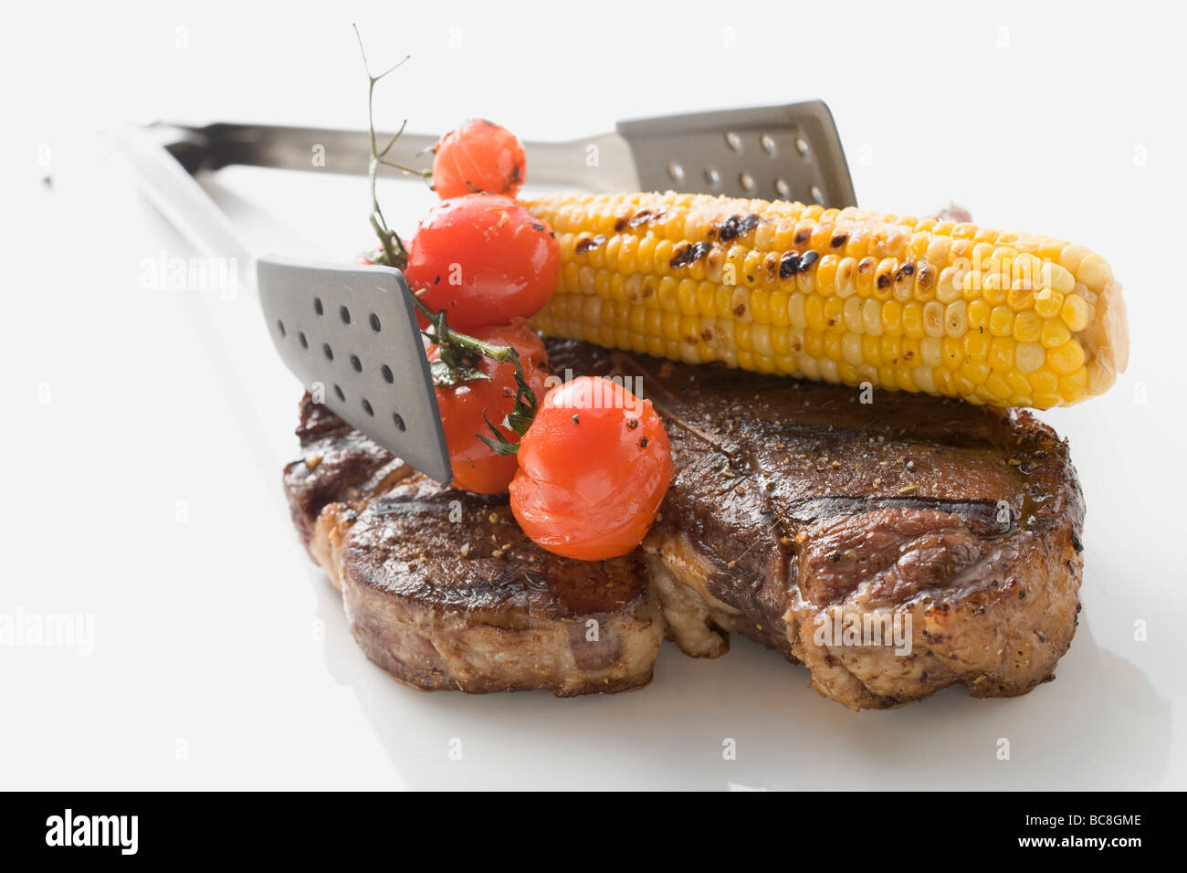 Grilled T-bone steak, corn on the cob, tomatoes, grill tongs Stock ...