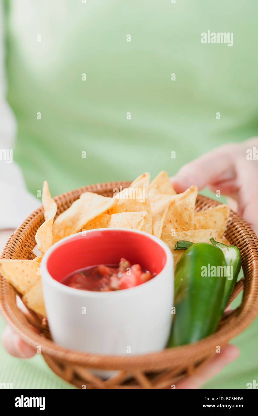 Woman holding basket of nachos with salsa and chilli Stock Photo - Alamy