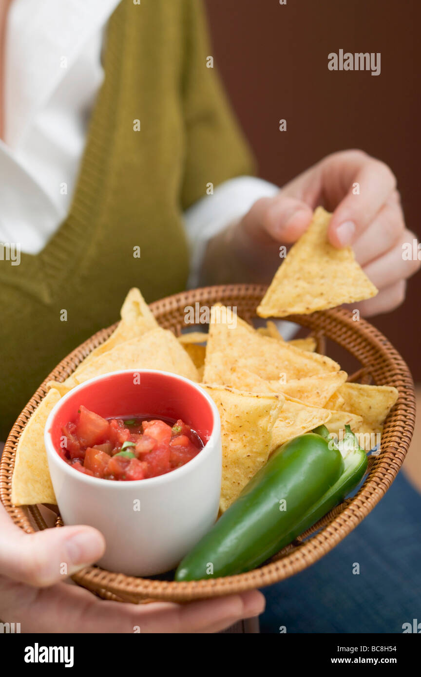 Woman holding basket of nachos with salsa and chilli Stock Photo - Alamy
