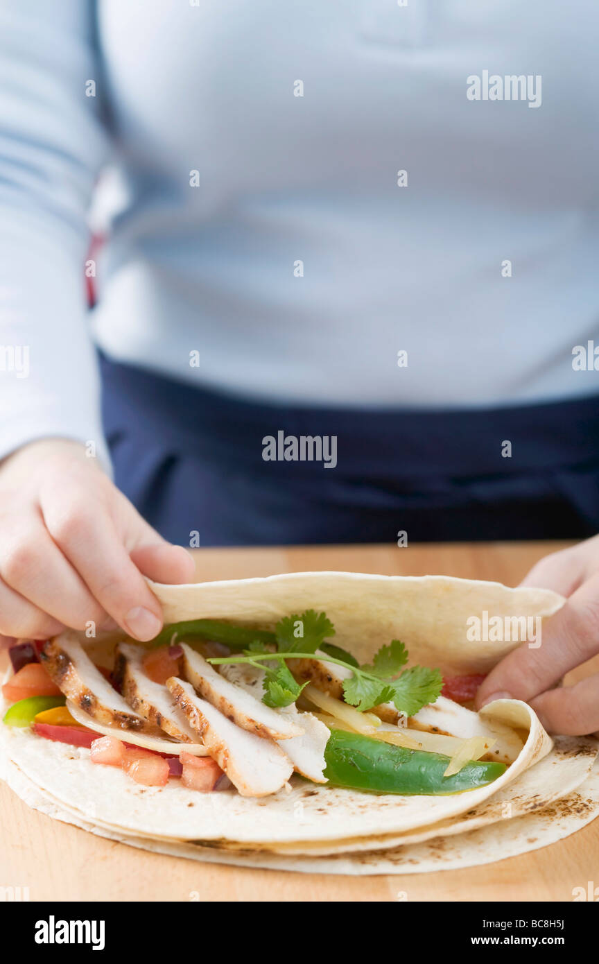Folding a tortilla over chicken filling Stock Photo - Alamy