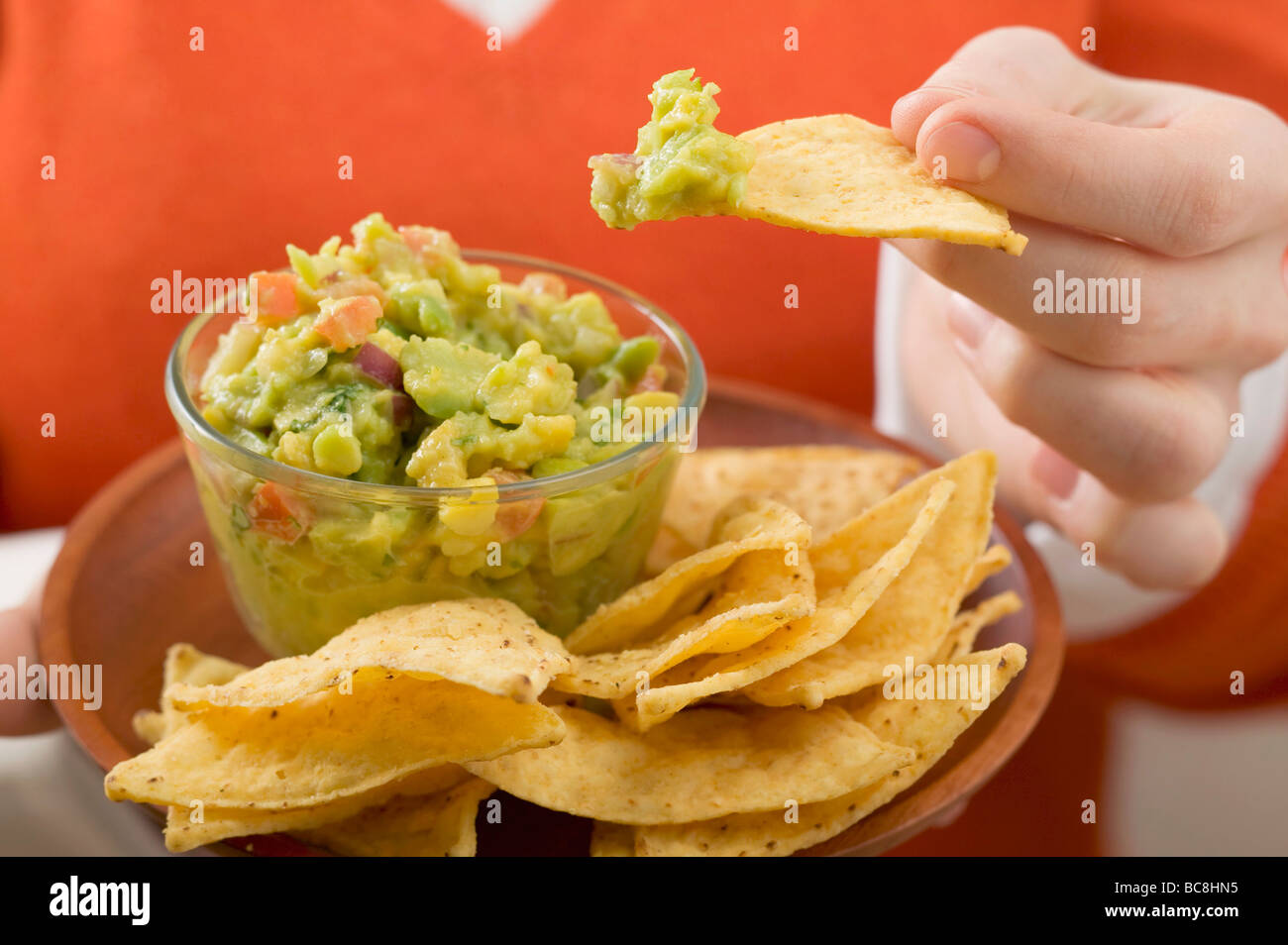 Woman dipping nacho in guacamole Stock Photo - Alamy