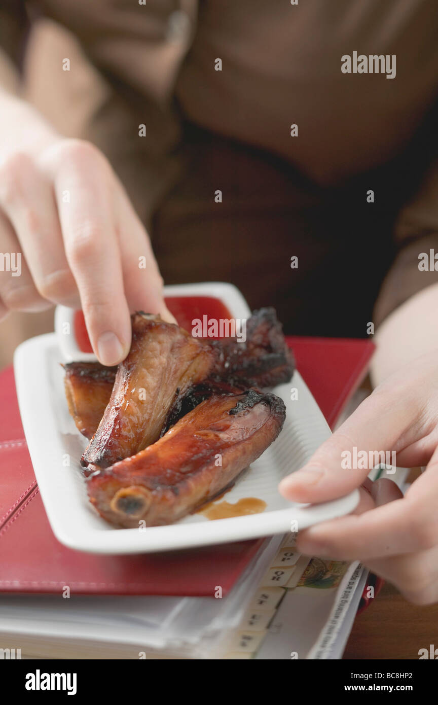 Woman eating glazed pork ribs in office Stock Photo - Alamy