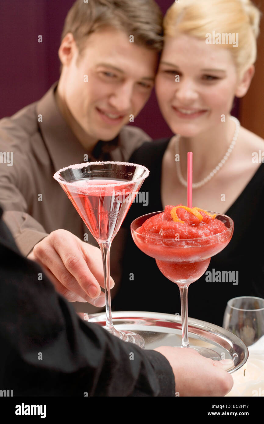 Waiter serving two drinks to romantic couple Stock Photo - Alamy