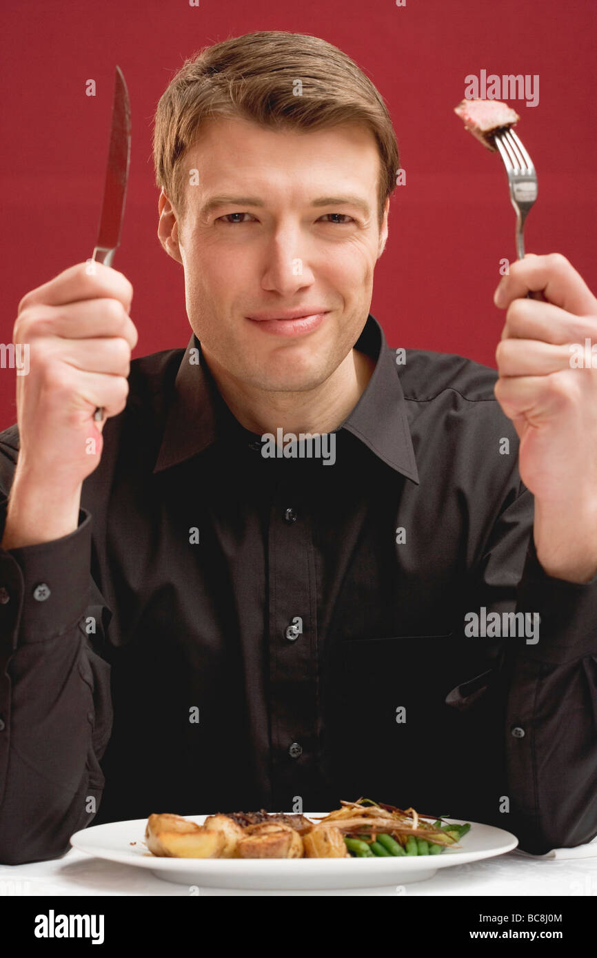 Man holding knife & fork with piece of beef steak on fork Stock Photo ...