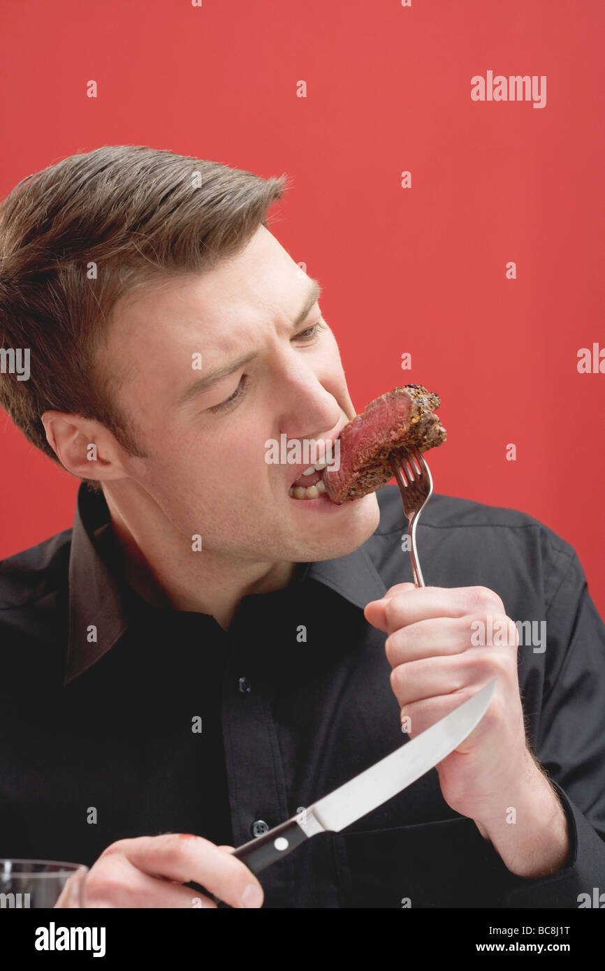 Man biting a tough piece of beef steak Stock Photo - Alamy