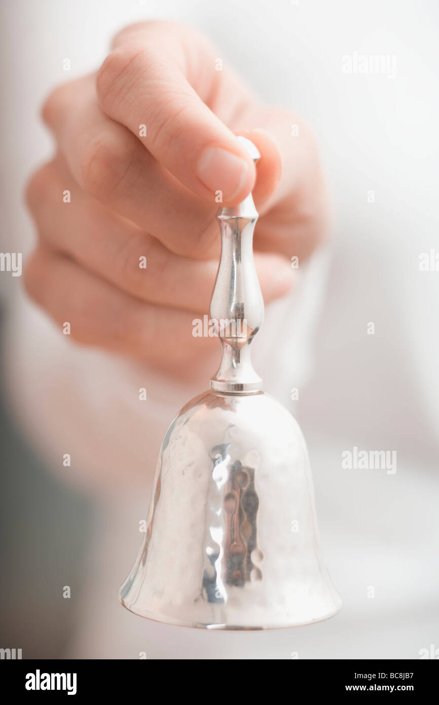 Hand holding silver bell Stock Photo - Alamy