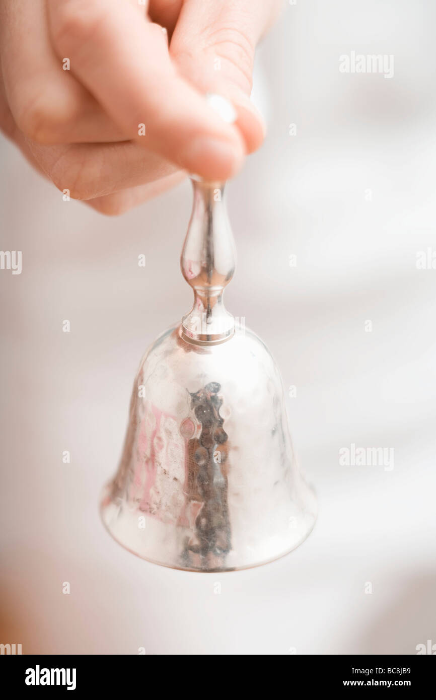 Hand holding silver bell Stock Photo - Alamy