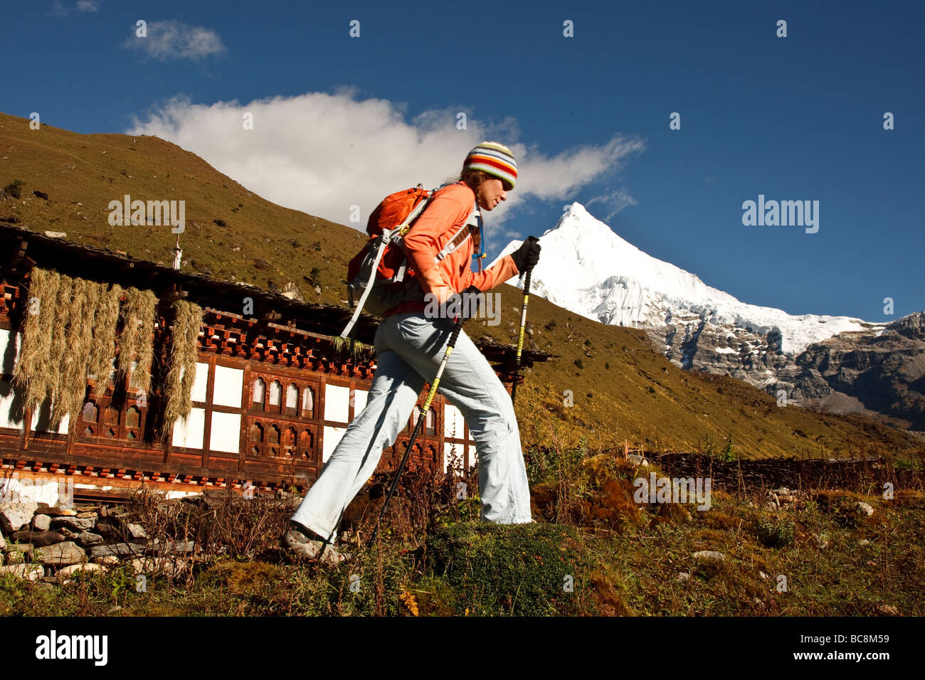 A woman hikes past a home with Mount Jitchu Drake in the distance while ...