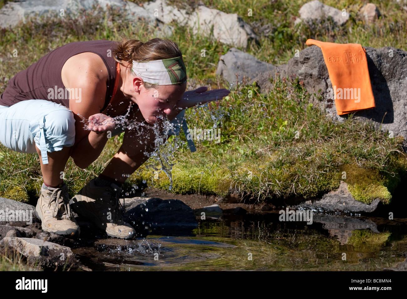 A woman washing her face in a smal creek along the Wonderland Trail ...