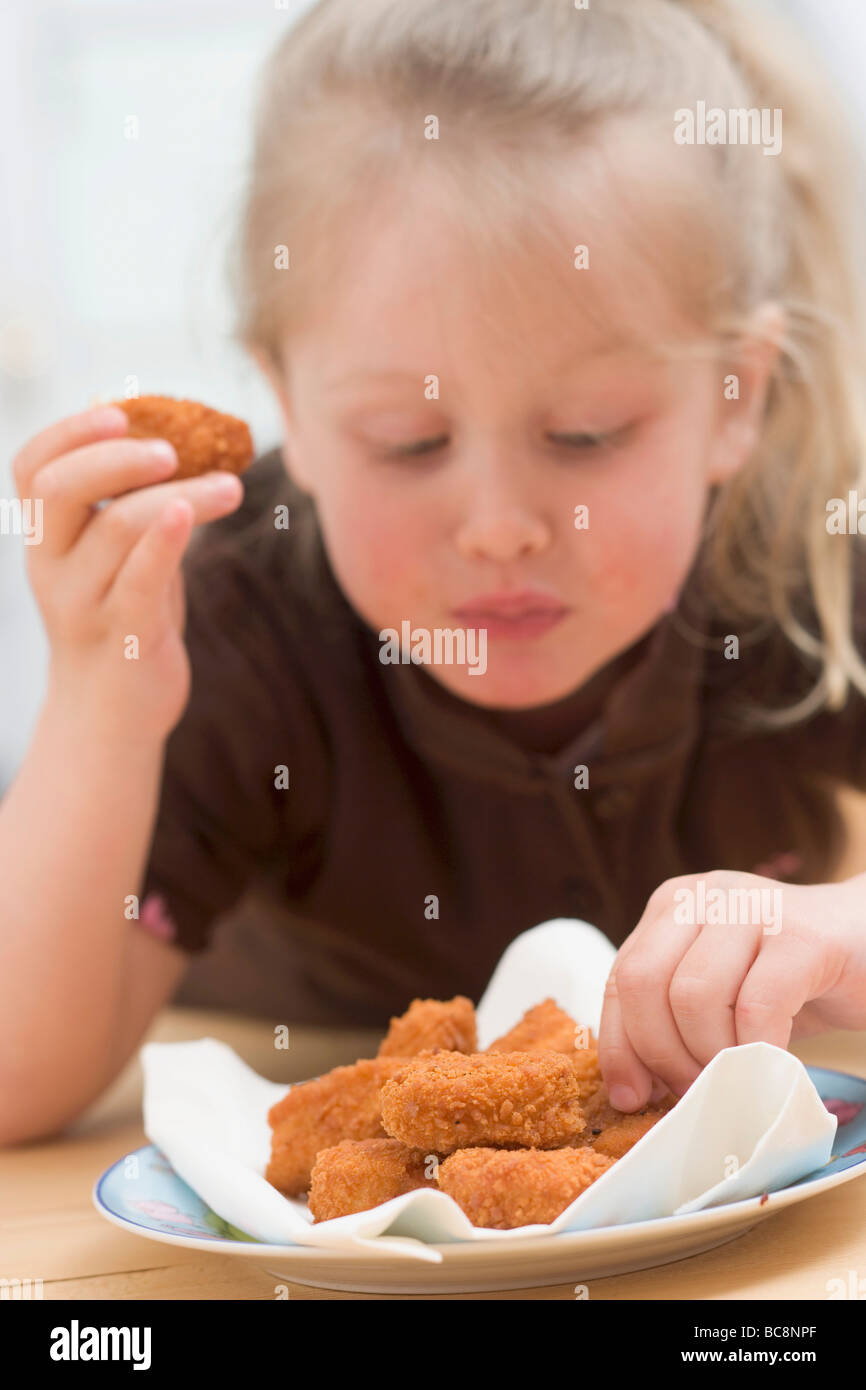 Little girl eating chicken nuggets Stock Photo - Alamy