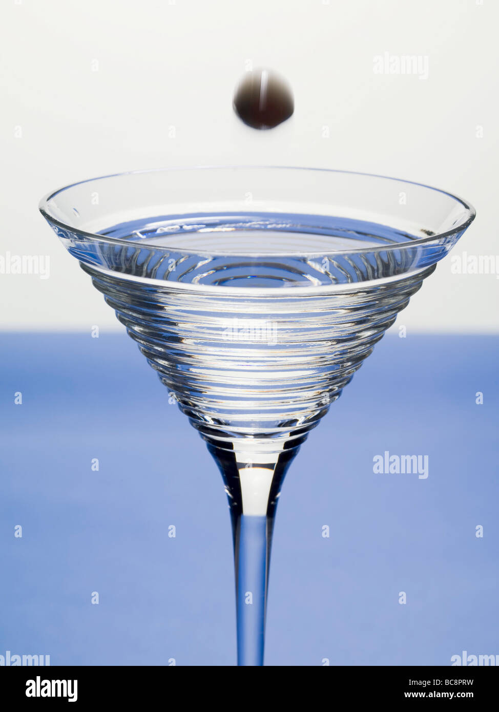 Olive falling into glass of Martini Stock Photo - Alamy
