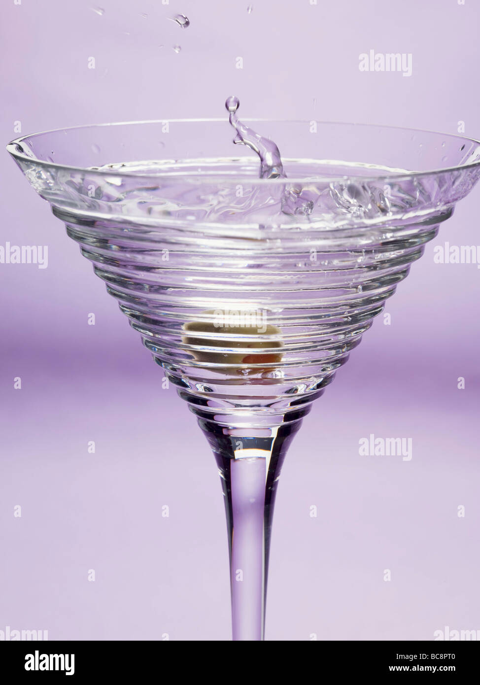 Olive falling into glass of Martini Stock Photo - Alamy