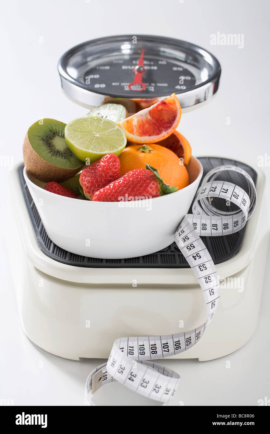 Bowl of fresh fruit and tape measure on scales Stock Photo - Alamy
