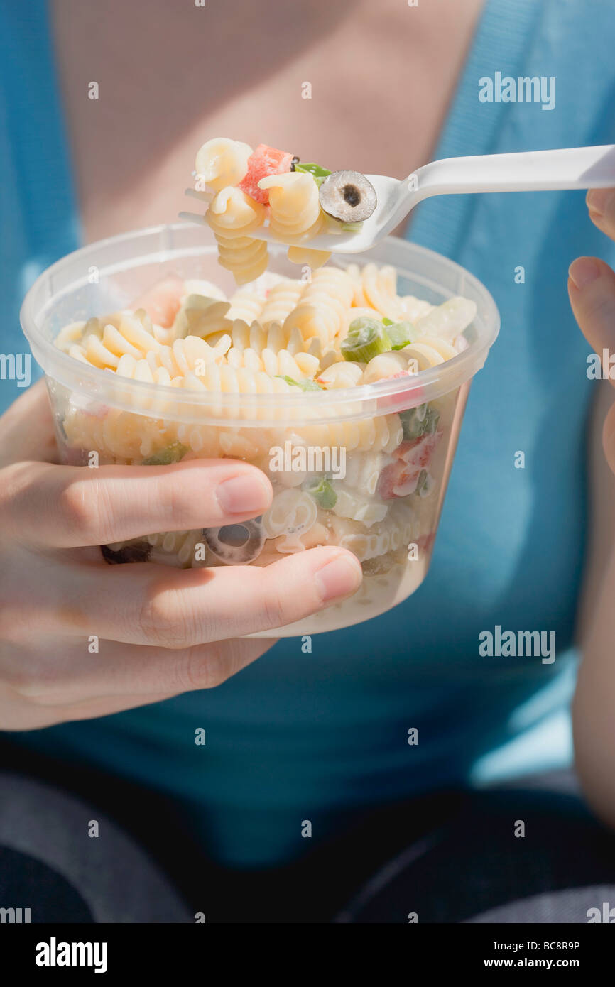 Woman eating pasta salad out of plastic tub Stock Photo - Alamy