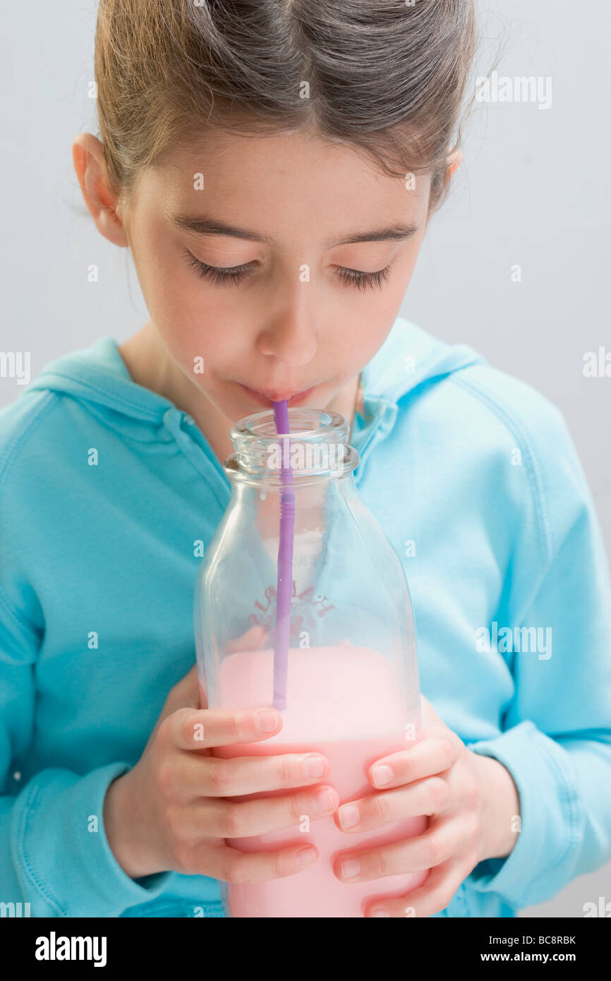 Little girl drinking strawberry milk out of bottle with straw Stock Photo - Alamy