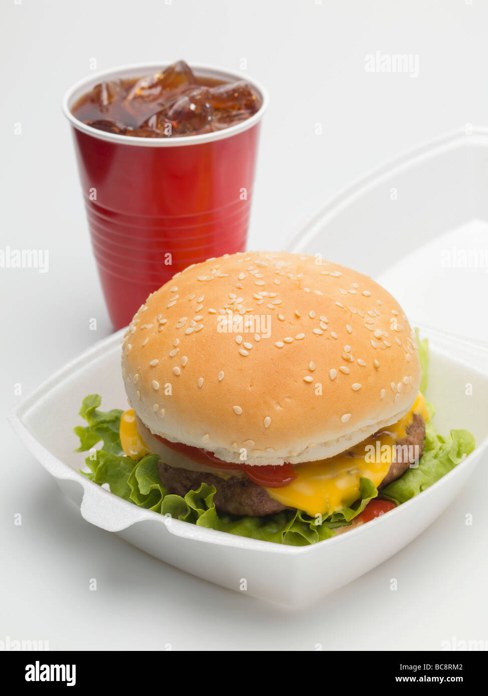 Cheeseburger in packaging, cola in plastic cup Stock Photo - Alamy