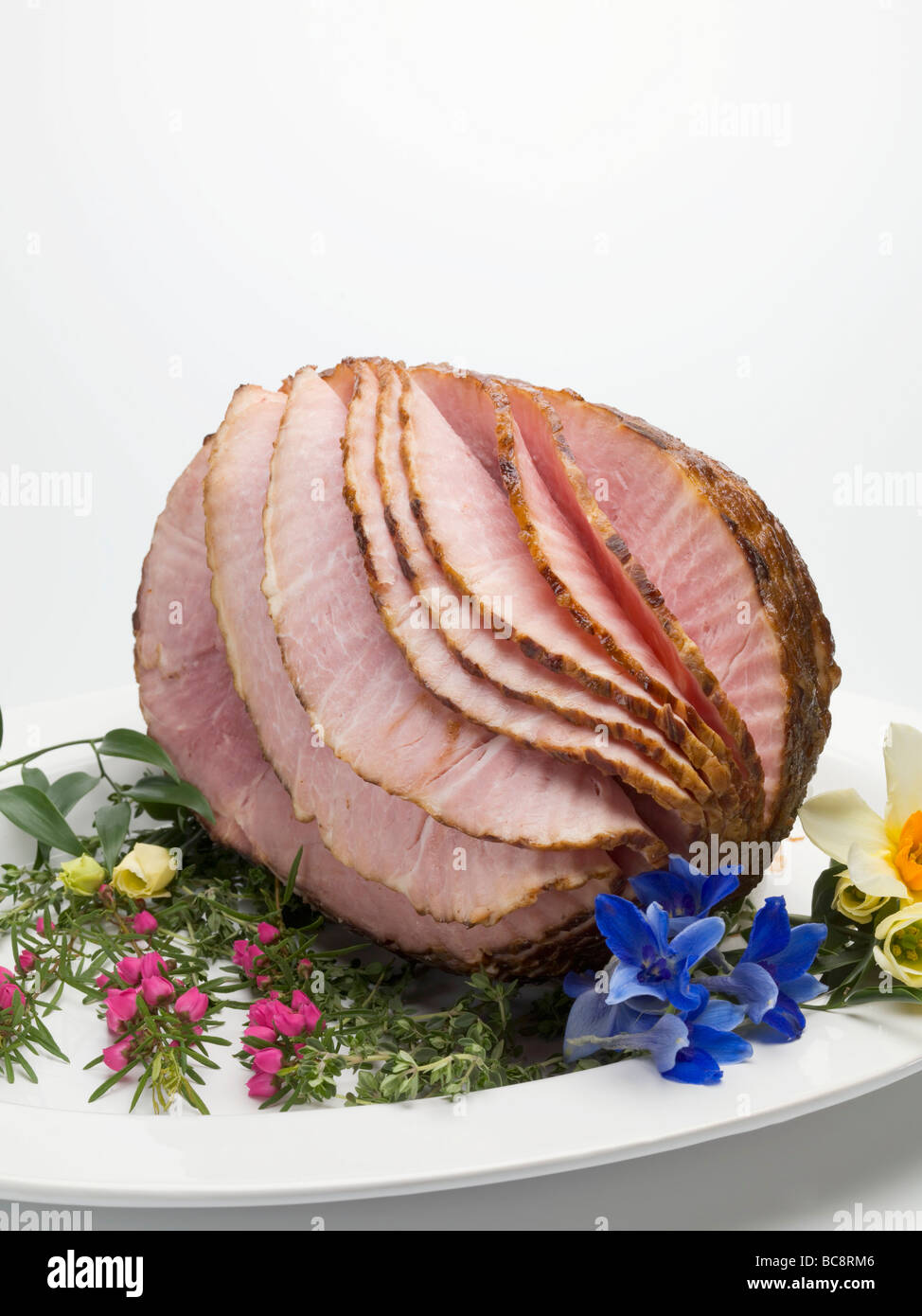 Roast ham, partly carved, on platter with edible flowers Stock Photo ...