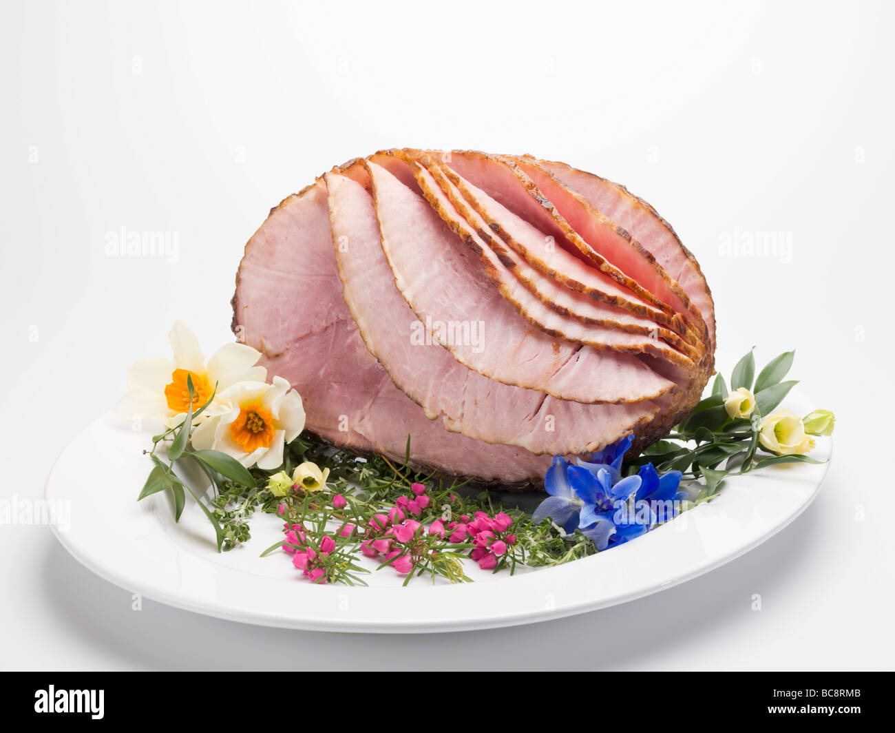 Roast ham, partly carved, on platter with edible flowers Stock Photo ...
