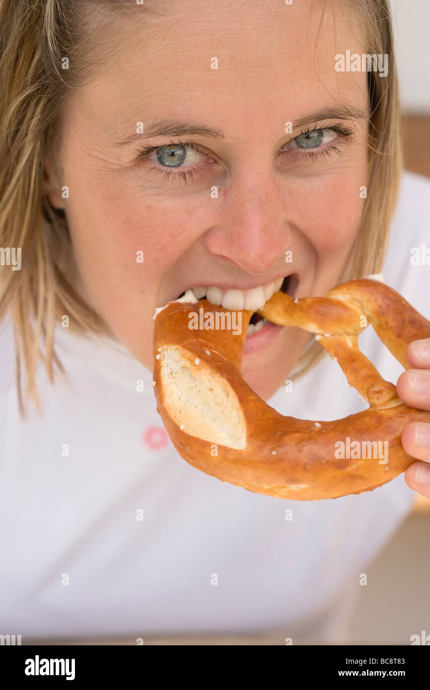 Woman biting into a pretzel Stock Photo - Alamy