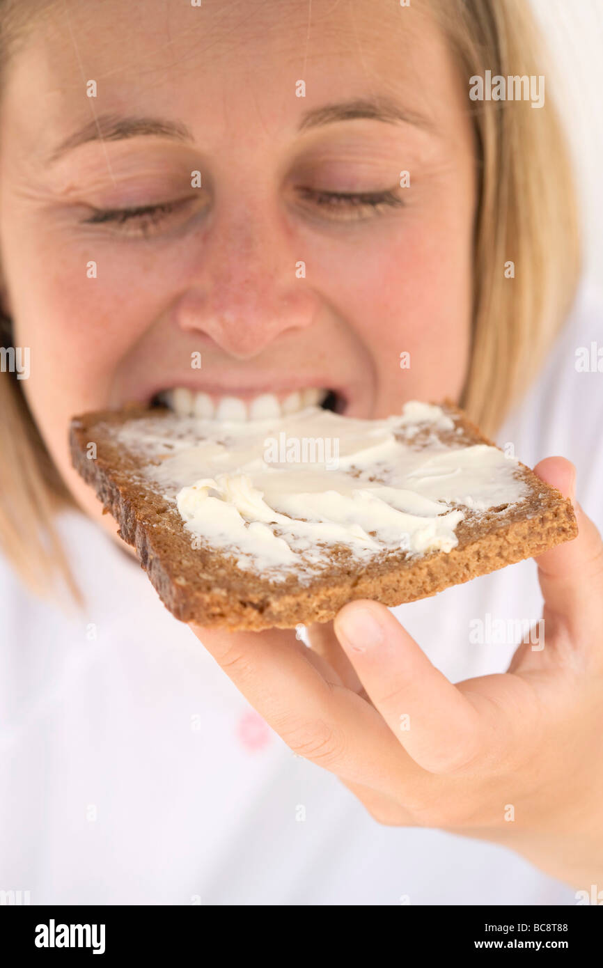 Woman biting into a slice of bread and butter Stock Photo - Alamy